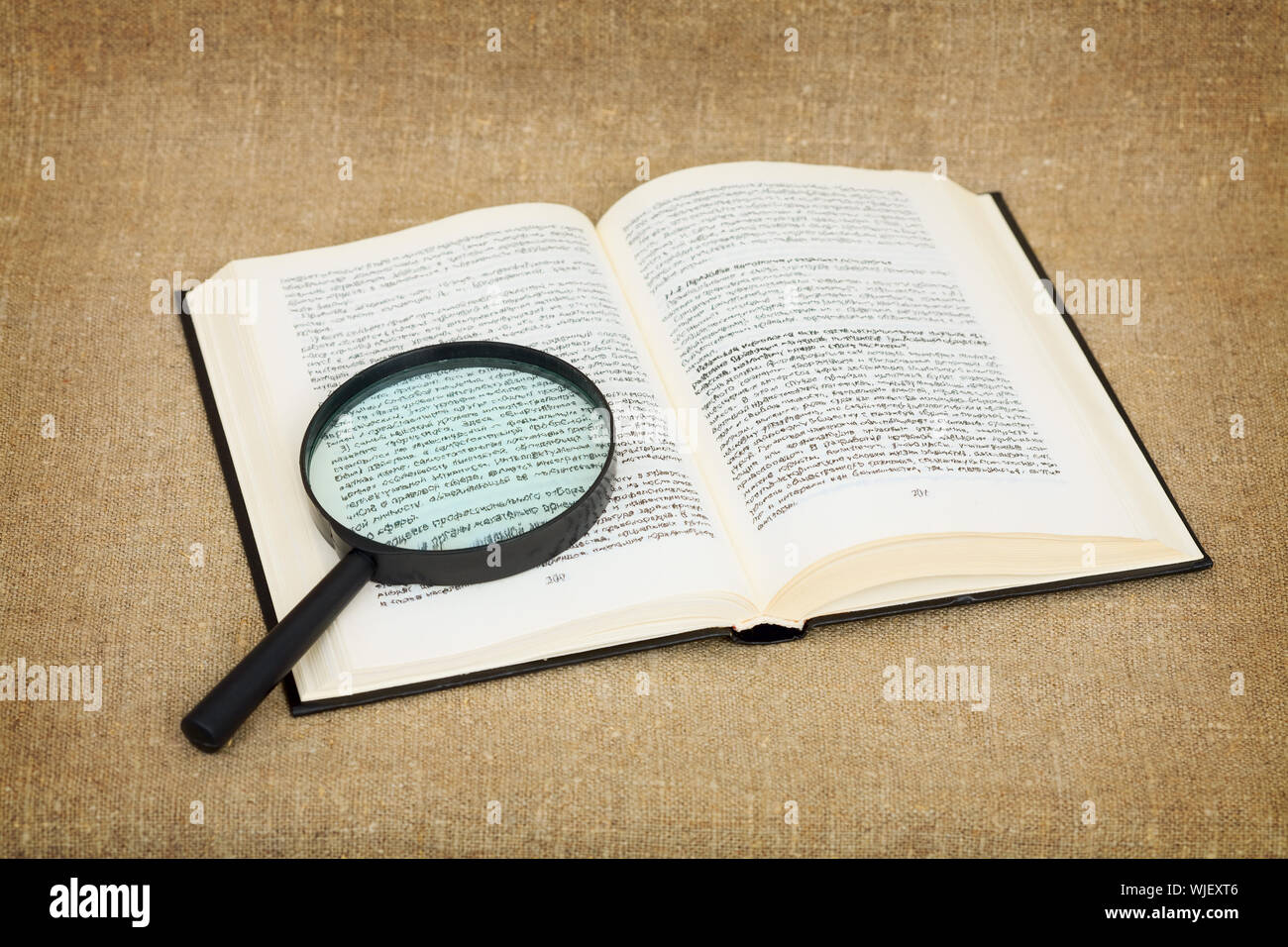 Open book and magnifier on canvas background - a still-life Stock Photo ...