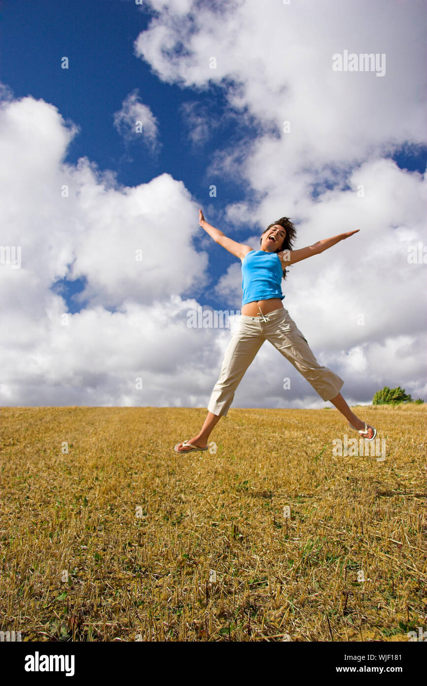 Beautiful woman jumping on a golden meadow Stock Photo - Alamy