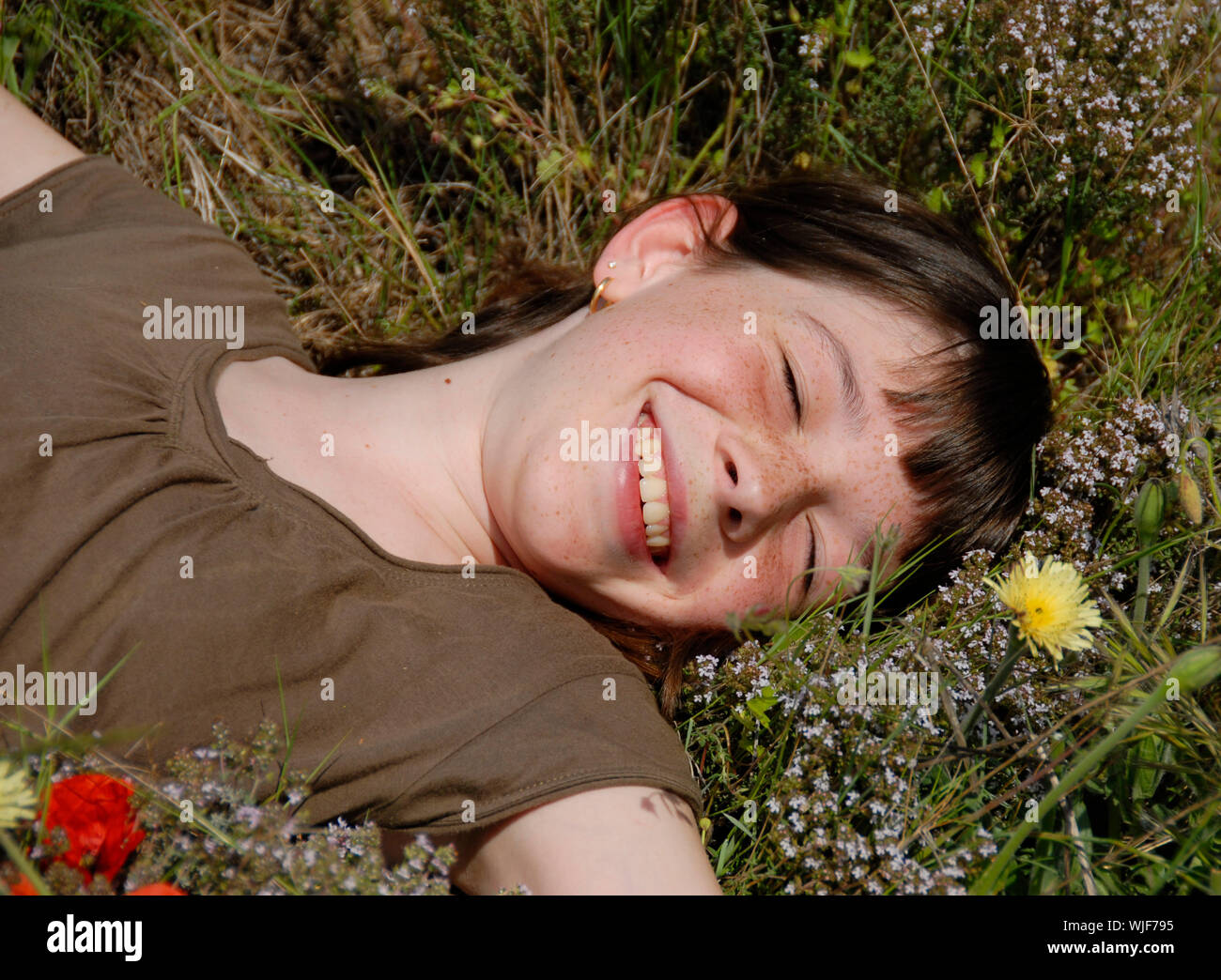 smiling girl laid down in a field with spring flowers Stock Photo - Alamy
