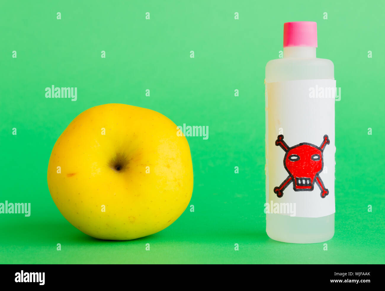concept of pesticide use on apple/ a apple with a bottle that contains ...