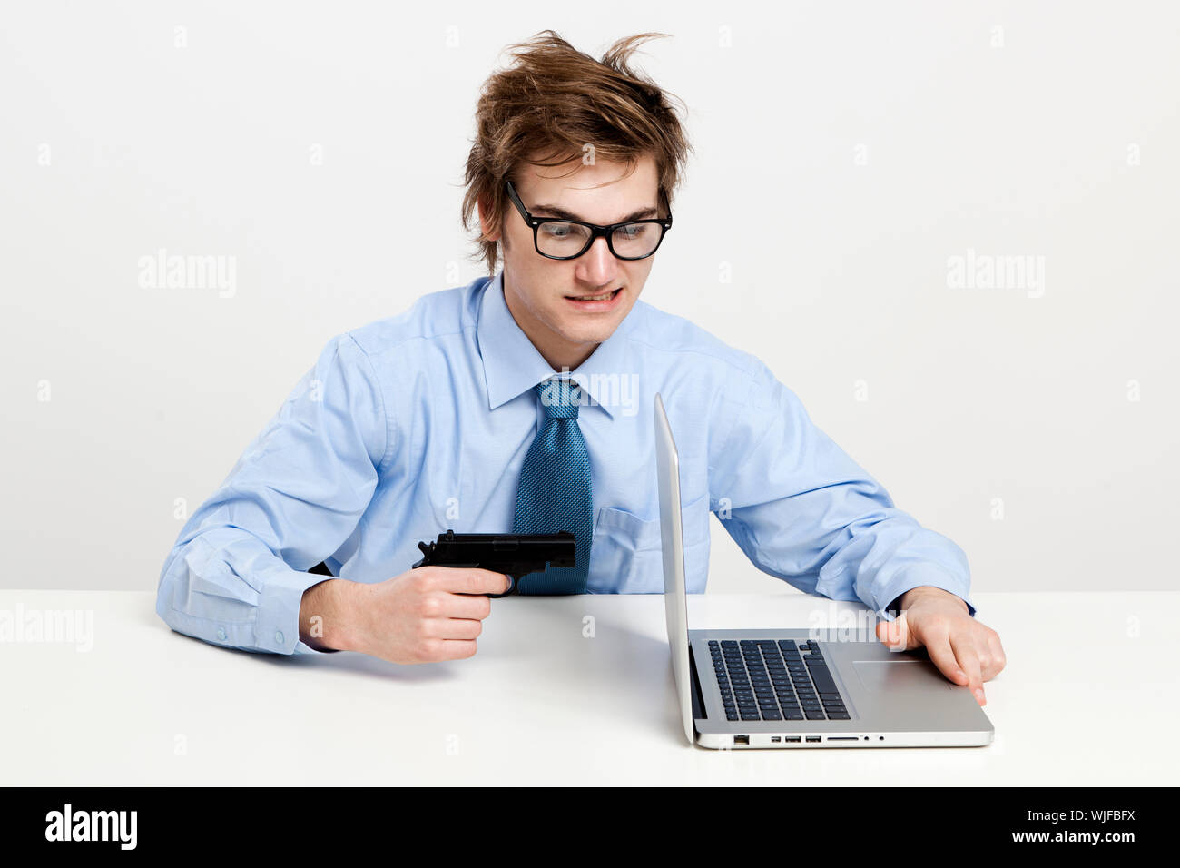 Young man in the office and pointing a gun to the laptop Stock Photo ...