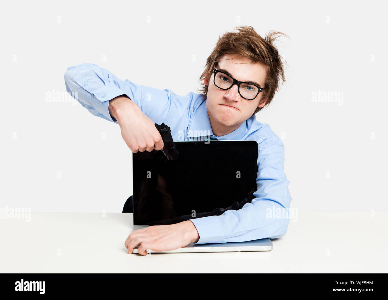 Young man in the office and pointing a gun to the laptop Stock Photo ...