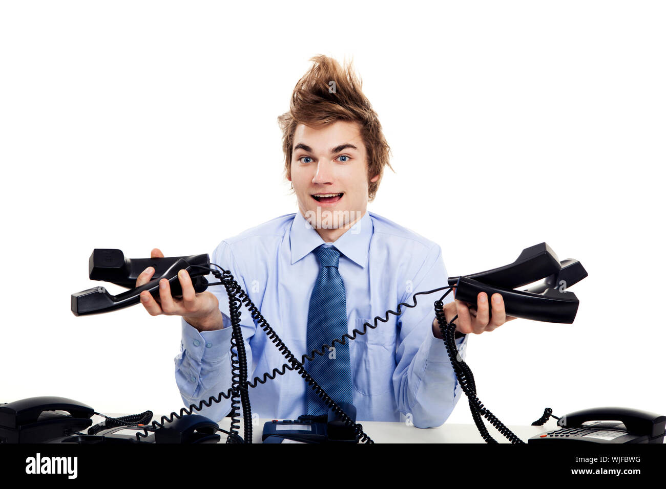 Young man sitting in the office and answering several phones at the ...