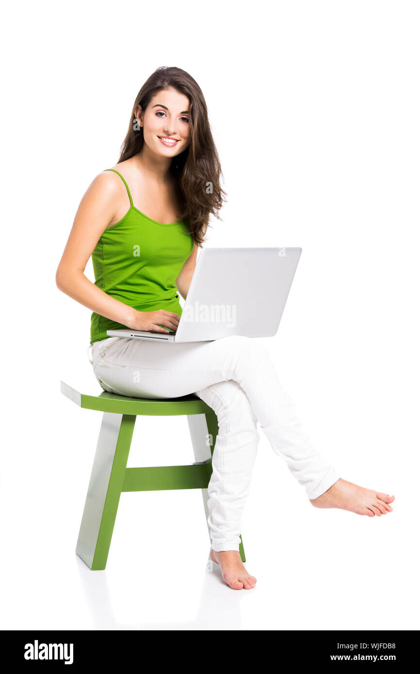 Beautiful woman sitting in a chair working with a laptop, isolated over ...