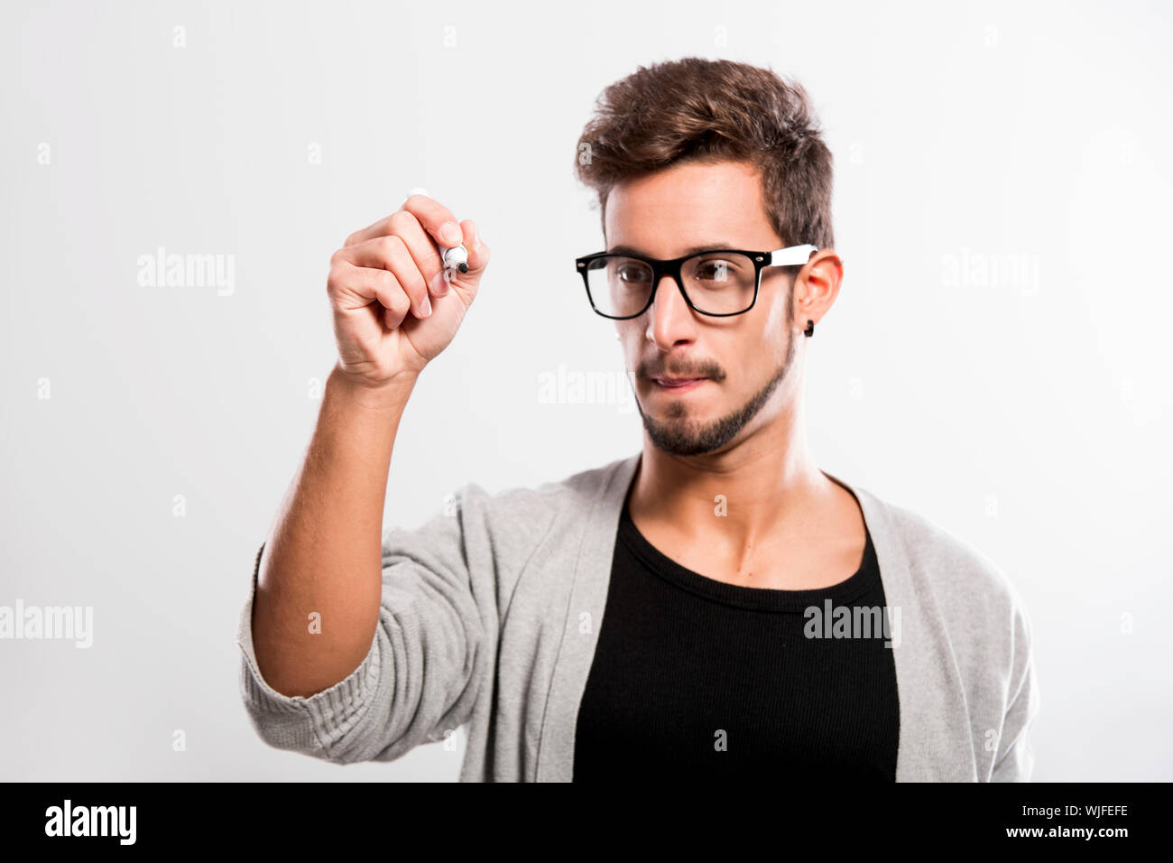 Portrait of a handsome young man wearing glasses and writting something ...