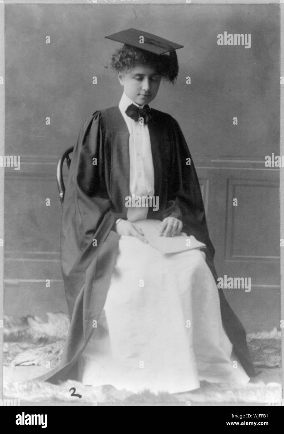 Helen Keller, full length portrait, seated in cap and gown Stock Photo ...