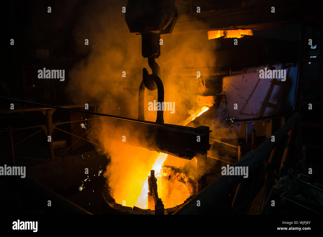 Molten steel pouring. Liquid hot metal of steel spills out of the ladle ...