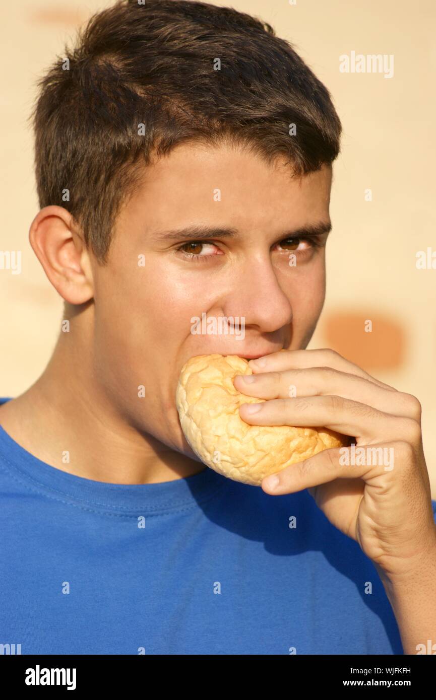 a male teenager eating a bread roll Stock Photo - Alamy