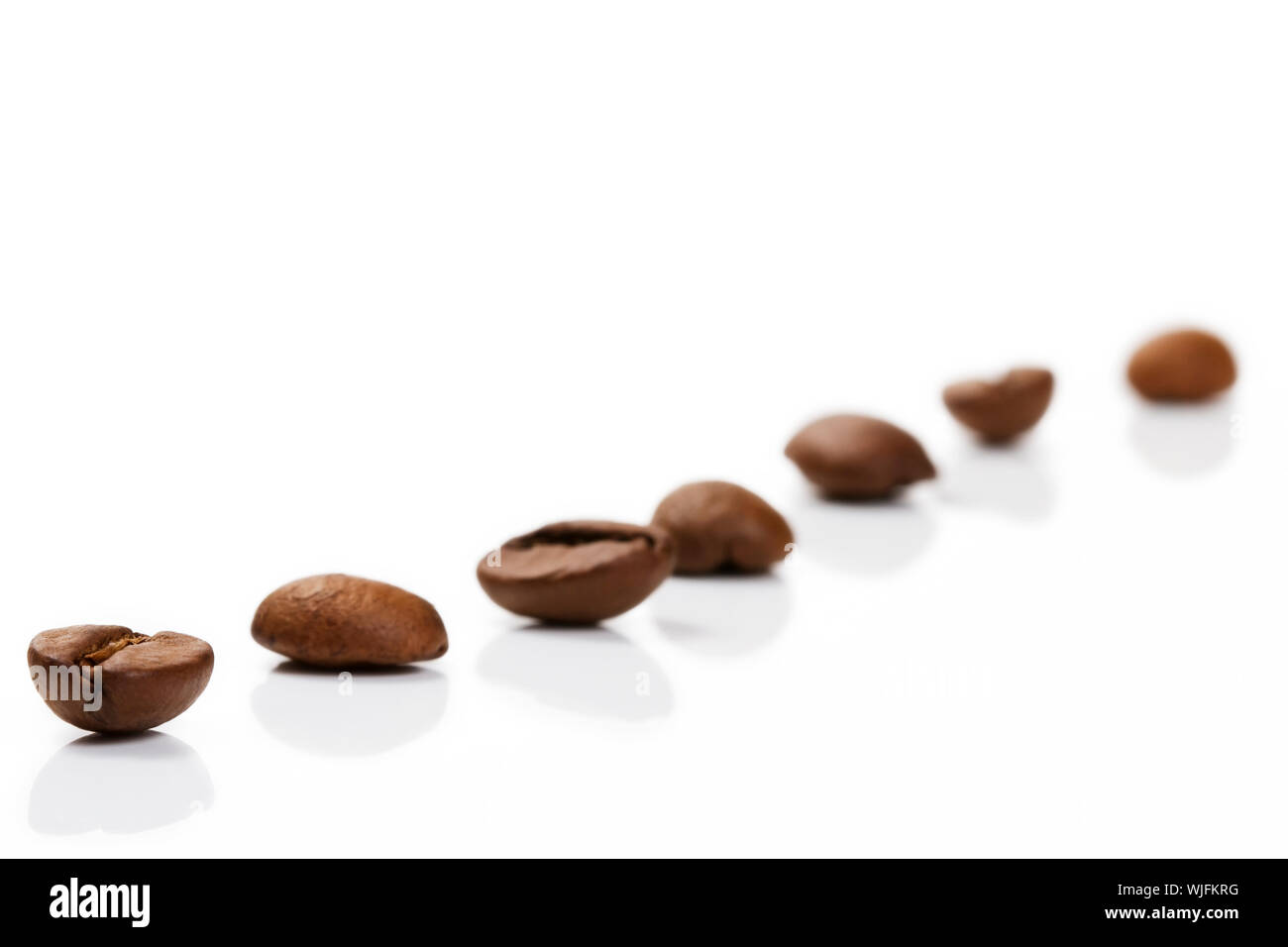 diagonal row of coffee beans on white background Stock Photo - Alamy