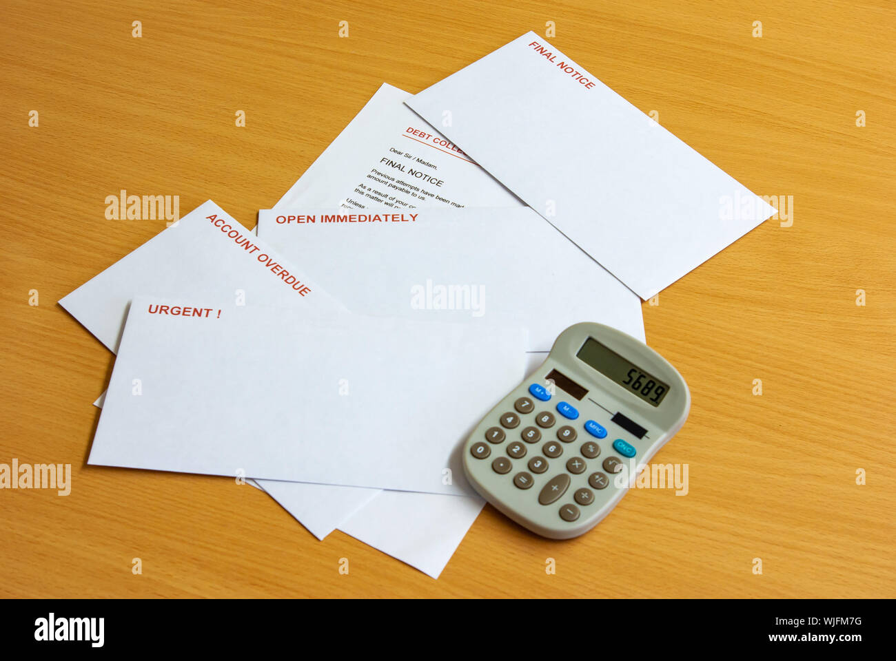 Urgent letters in envelopes with calculator on a beech desktop Stock ...