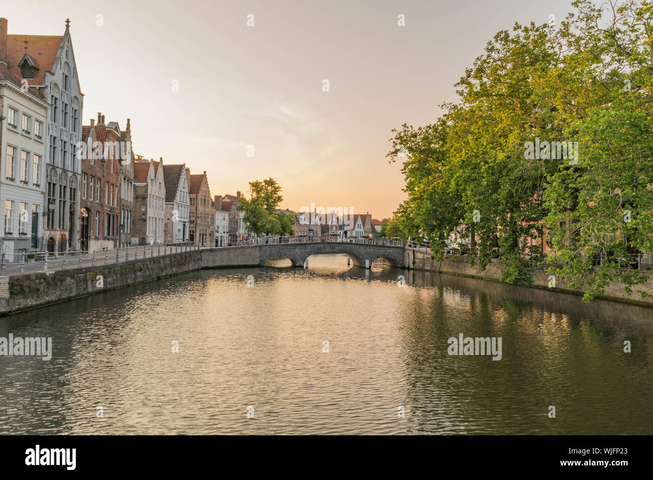 Beautiful canal with colorful stone two-story houses, trees and a stone ...