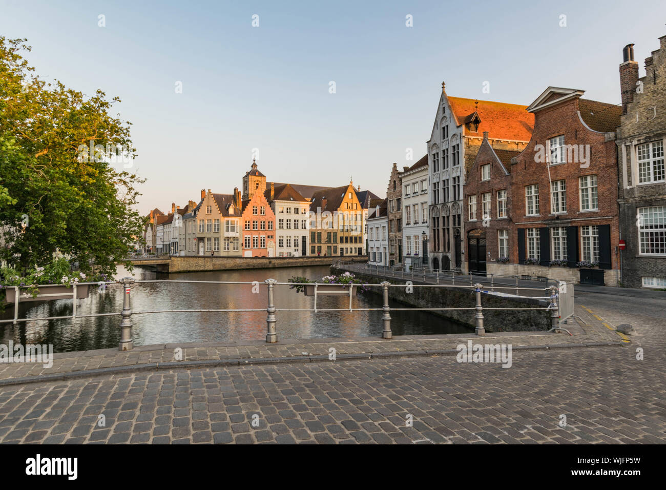 Beautiful canal with colorful stone two-story houses, trees and a stone ...