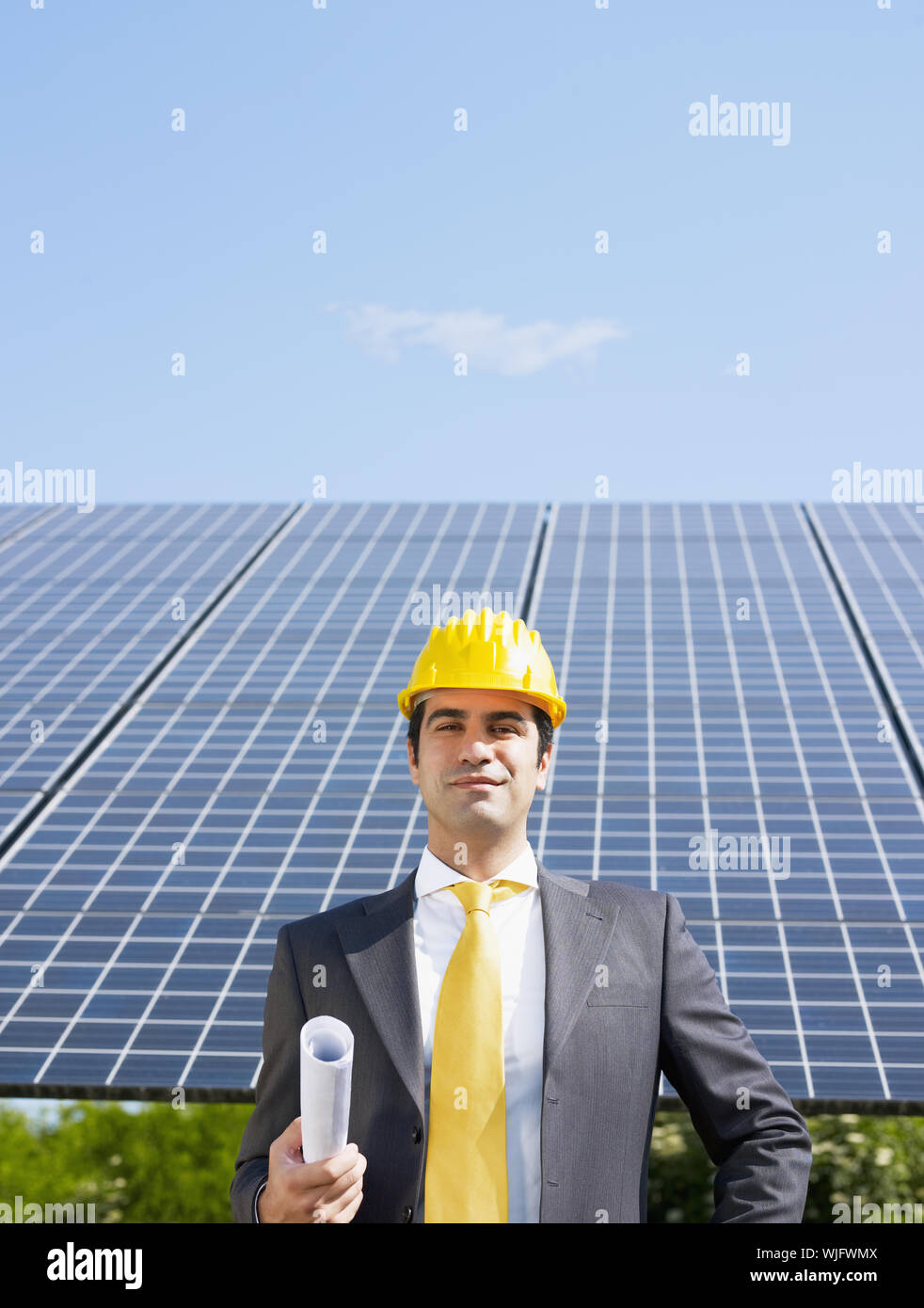 Portrait of mid adult italian male engineer holding blueprints in solar ...