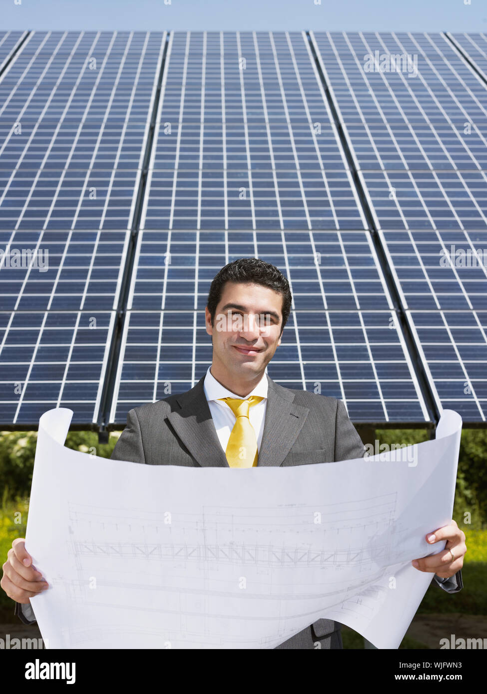 Portrait of mid adult italian male engineer reading blueprints in solar ...