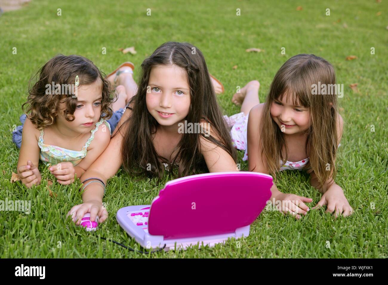 Three little girl outdoor playing with toy computer in grass Stock ...