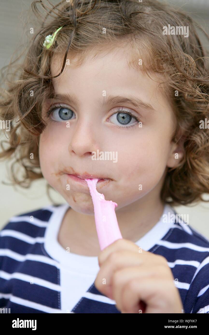 Little blue eyes girl eating sweet candy with dirty face Stock Photo ...
