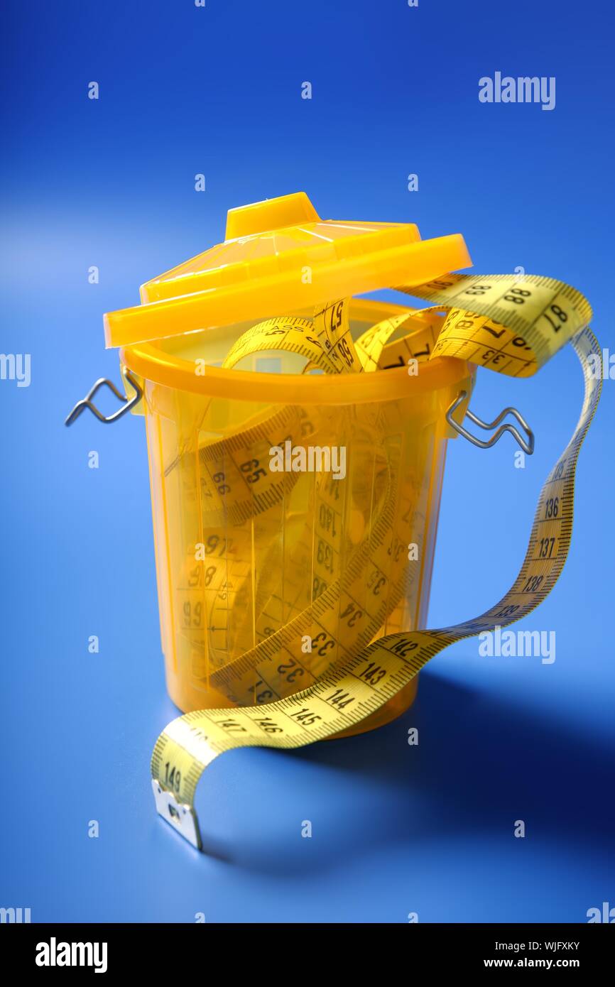 Centimeter tape meter on the trash, end of diet care metaphor Stock ...