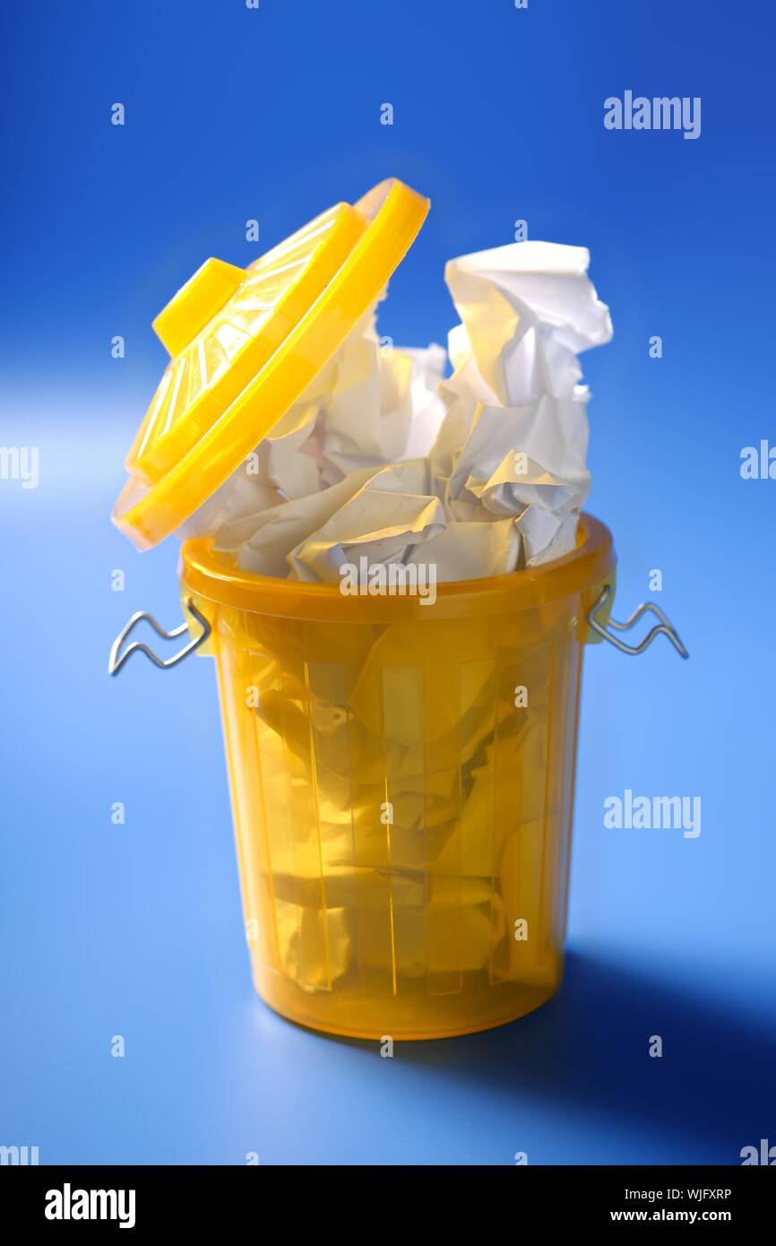 Paper trash in yellow over blue background, business metaphor Stock ...