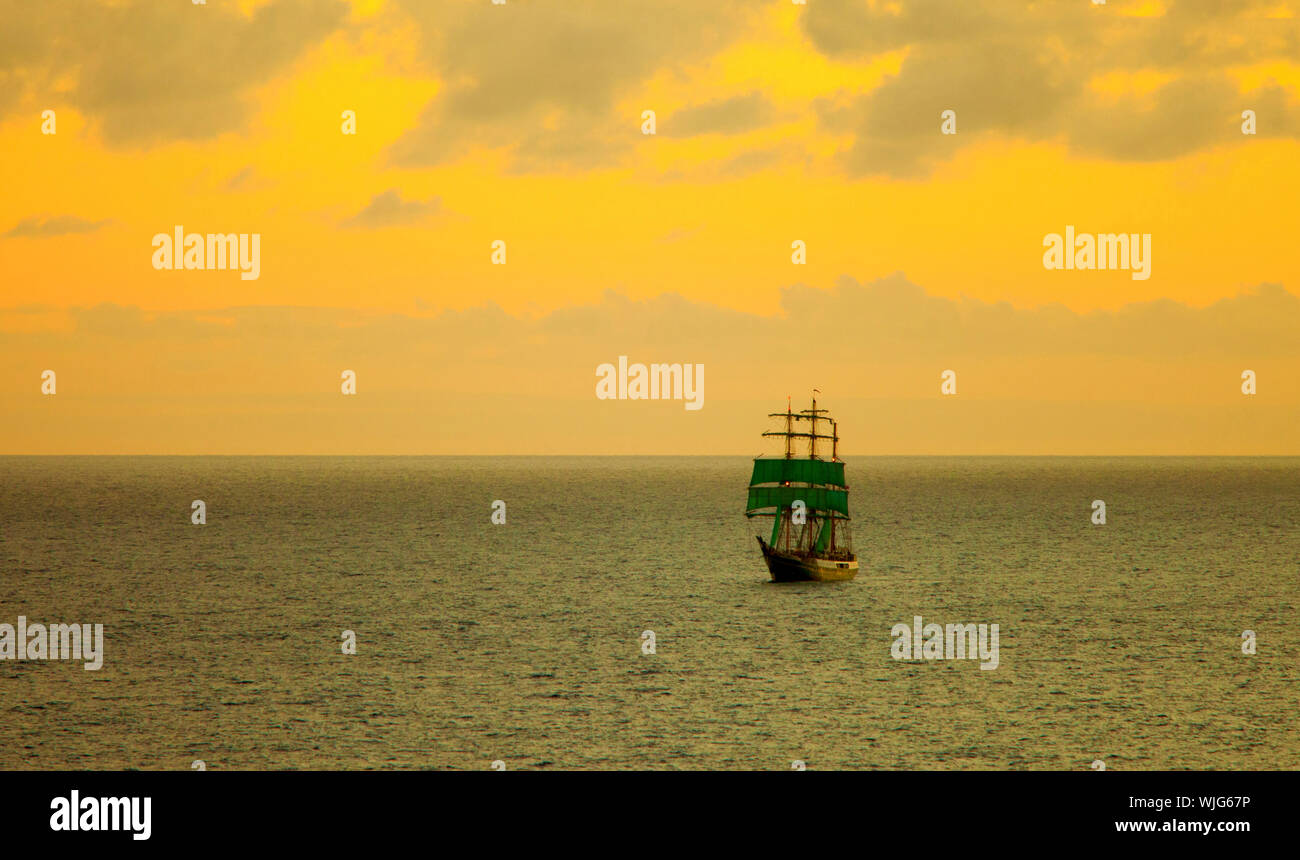 low aerial view of tall sailing ship at sea at sunset with room for ...