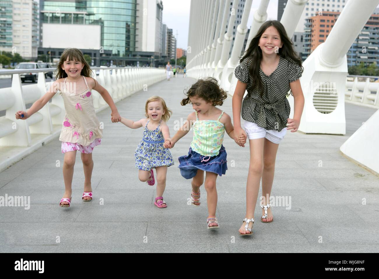 Four little girl group walking in the city bridge downtown buildings ...