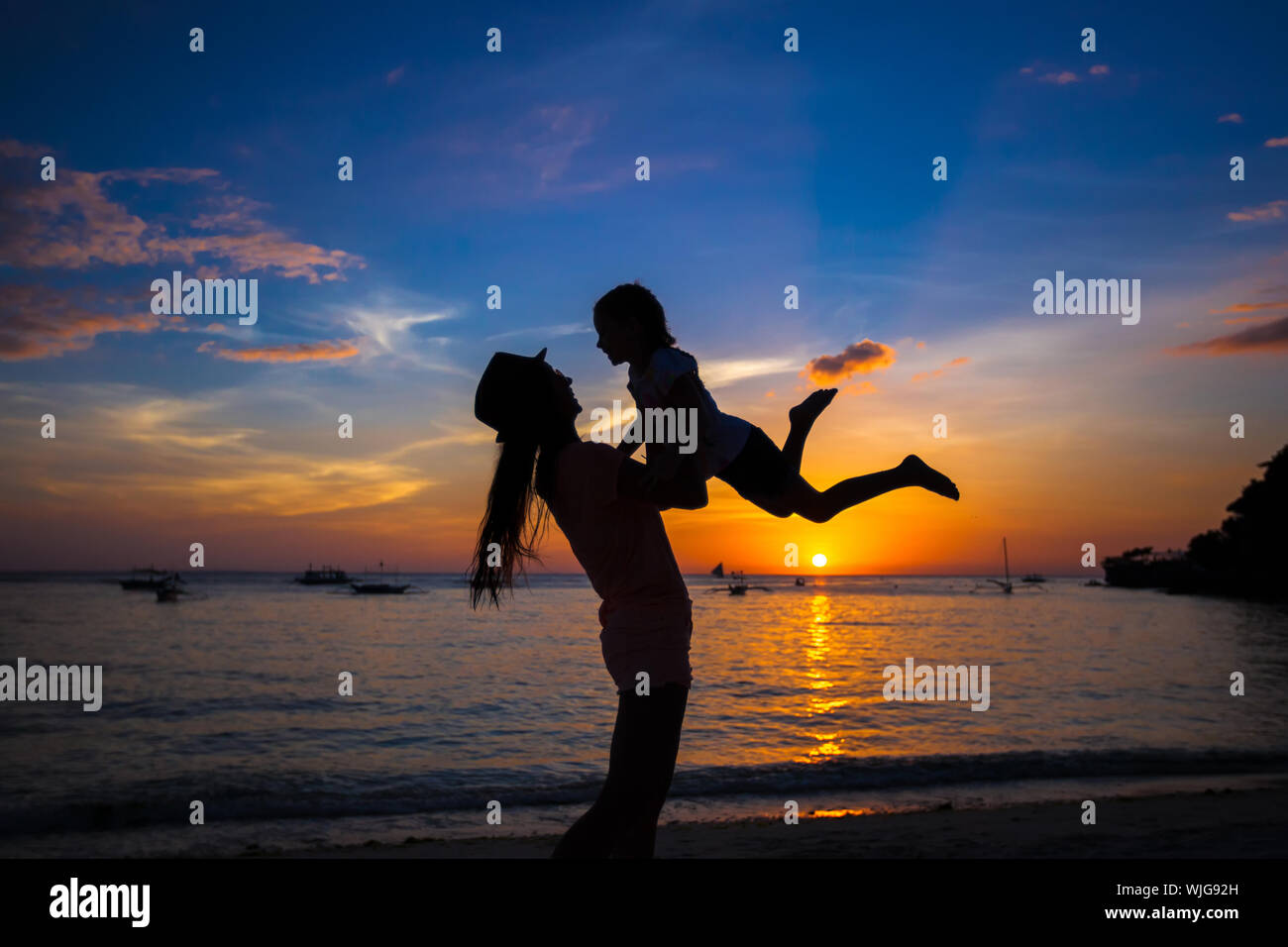 Little girl and her mother having fun at sunset on the island Boracay ...