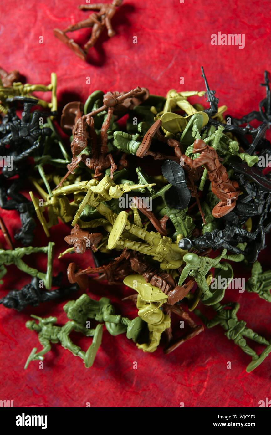 Metaphor of dead plastic toy war soldiers on a red bloody background ...