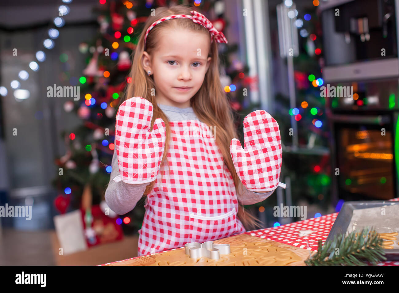 Adorable little girl in wore mittens baking Christmas gingerbread ...