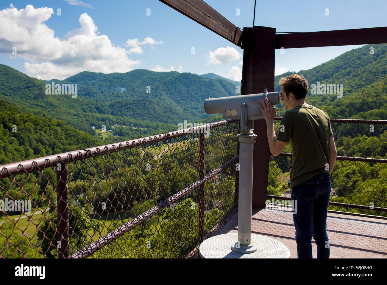Man looking through telescope on observation deck over forest Stock ...