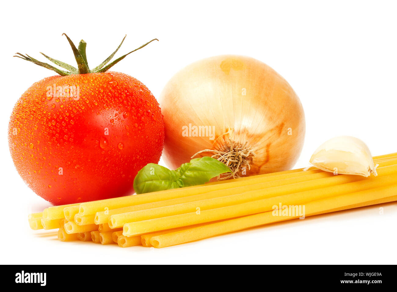 raw macaroni with basil, wet tomato, onion and garlic clove on white ...