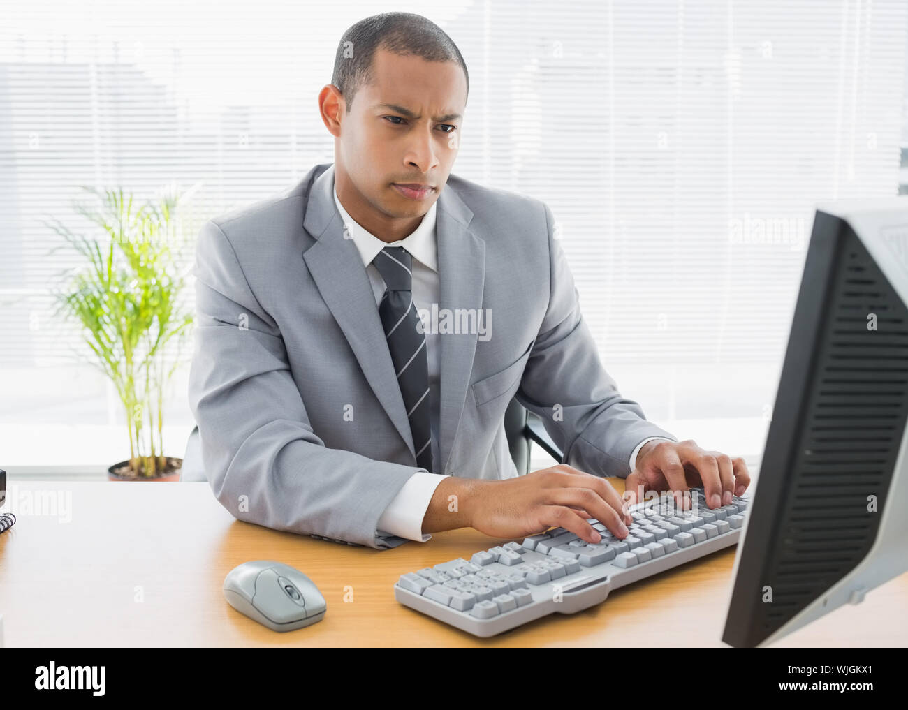 Concentrated young businessman using computer at office desk Stock ...