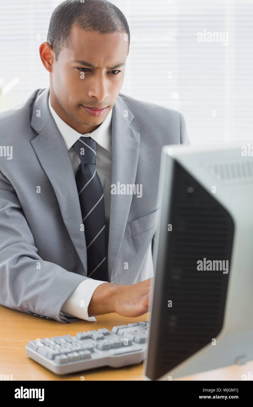 Concentrated young businessman using computer at office desk Stock ...