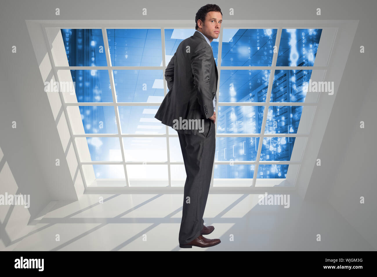 Businessman with hands on hips against server hallway seen through ...