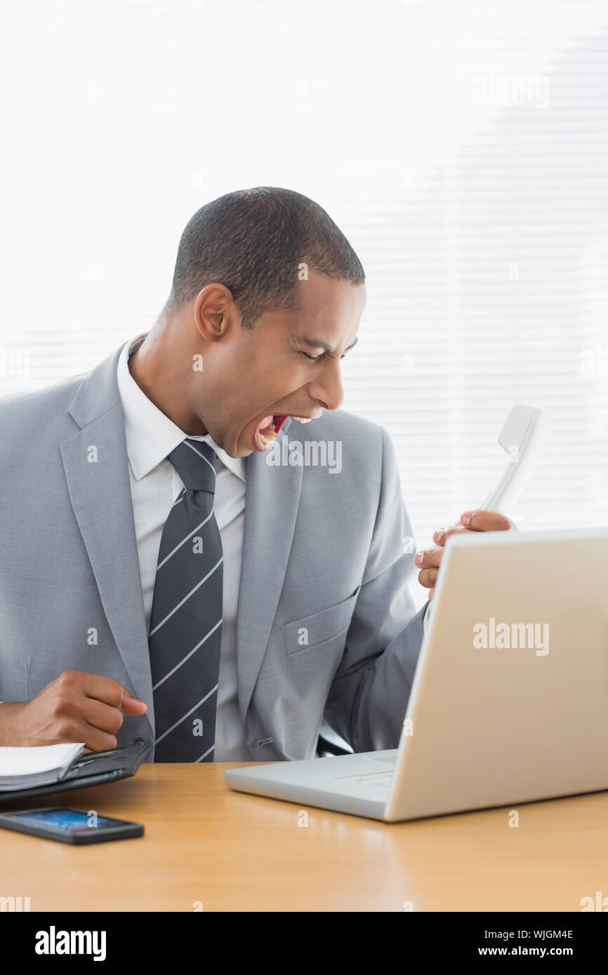 Elegant young businessman shouting into the phone at a bright office ...