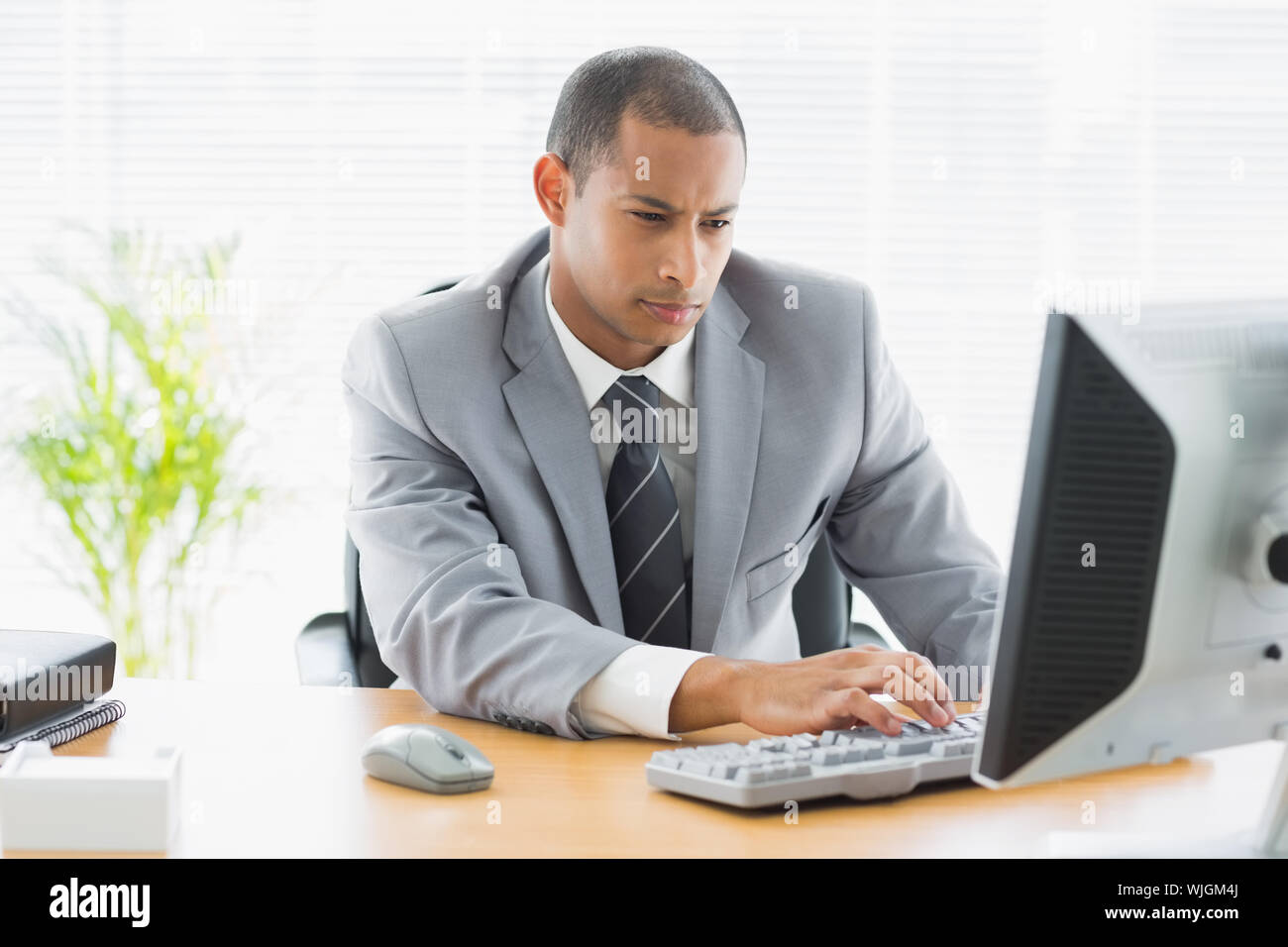 Concentrated young businessman using computer at office desk Stock ...