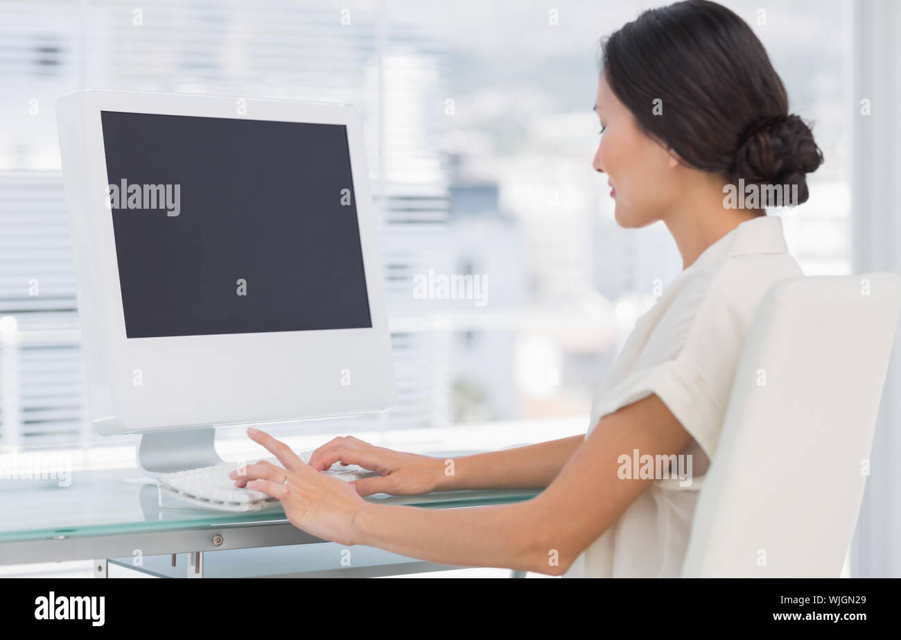 Side view of a young businesswoman using computer in a bright office ...