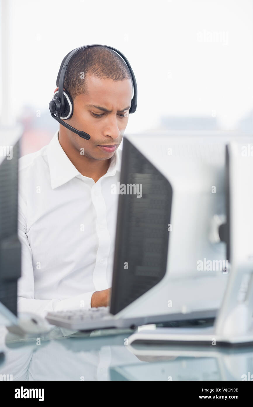 Concentrated male executive with headset using computer at office desk ...