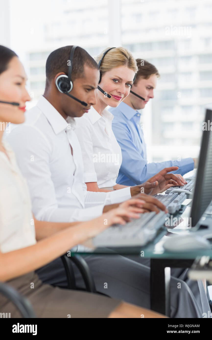 Side view portrait of business colleagues with headsets using computers ...