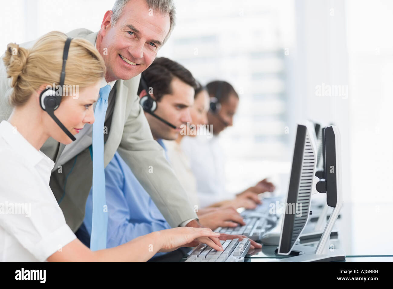 Manager looking at executives with headsets using computers in the ...