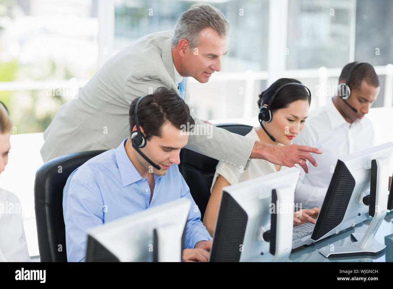 Manager looking at executives with headsets using computers in the ...
