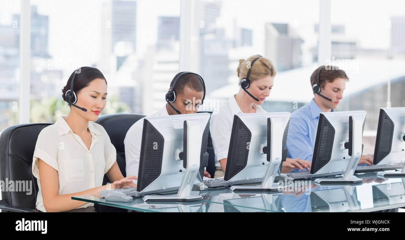 Group of business colleagues with headsets using computers at office ...