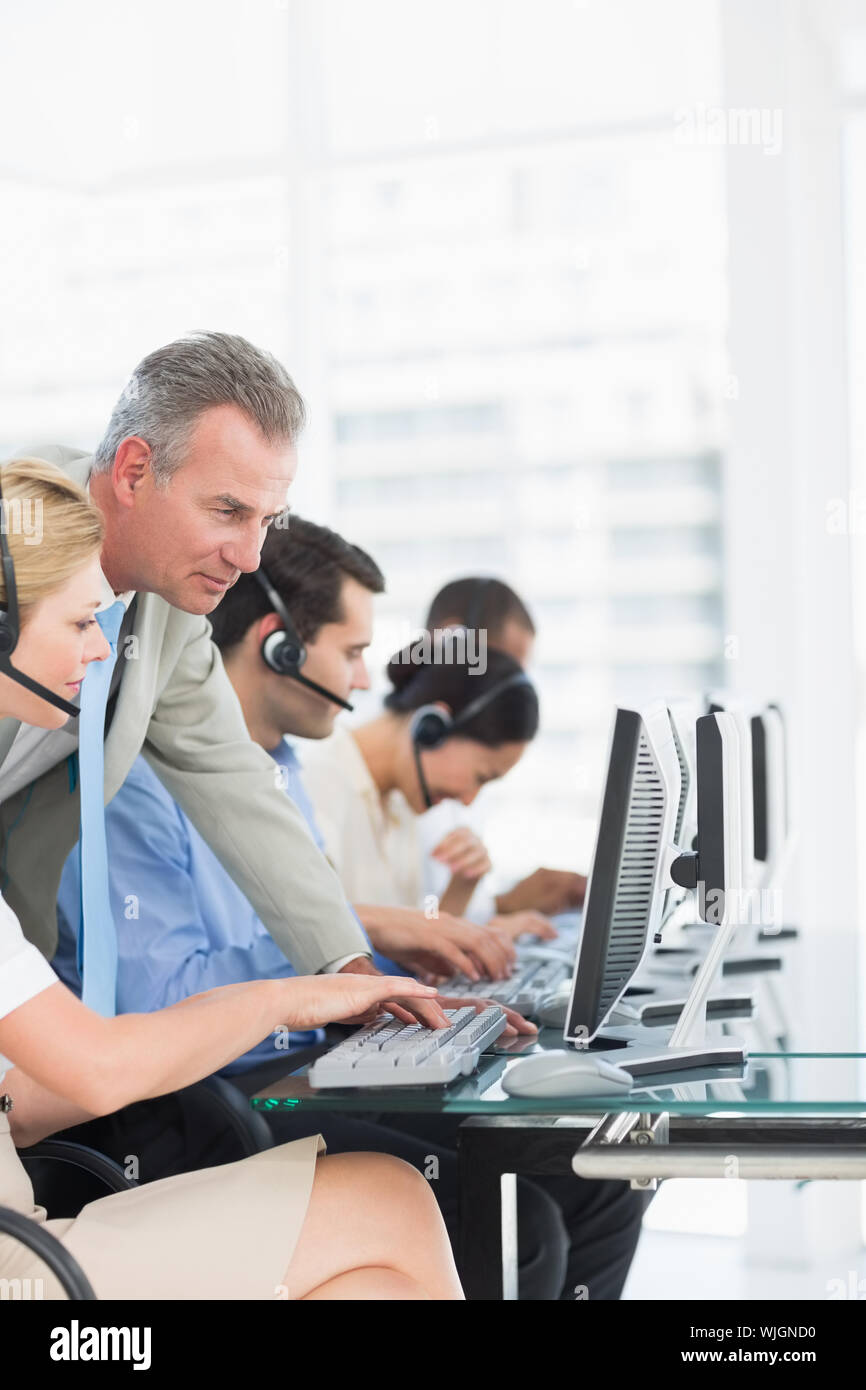 Side view of manager and executives with headsets using computers in ...