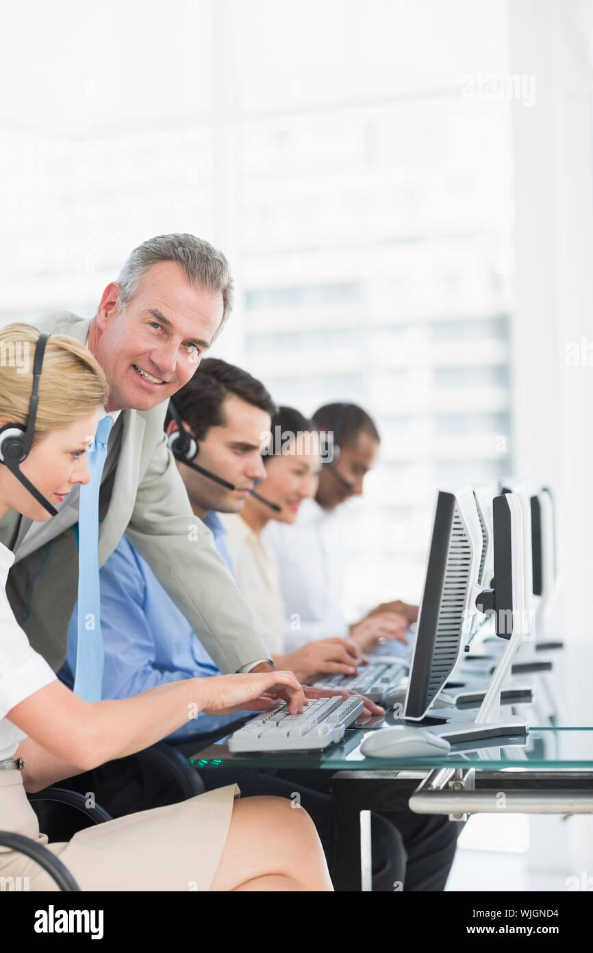 Side view of manager and executives with headsets using computers in ...