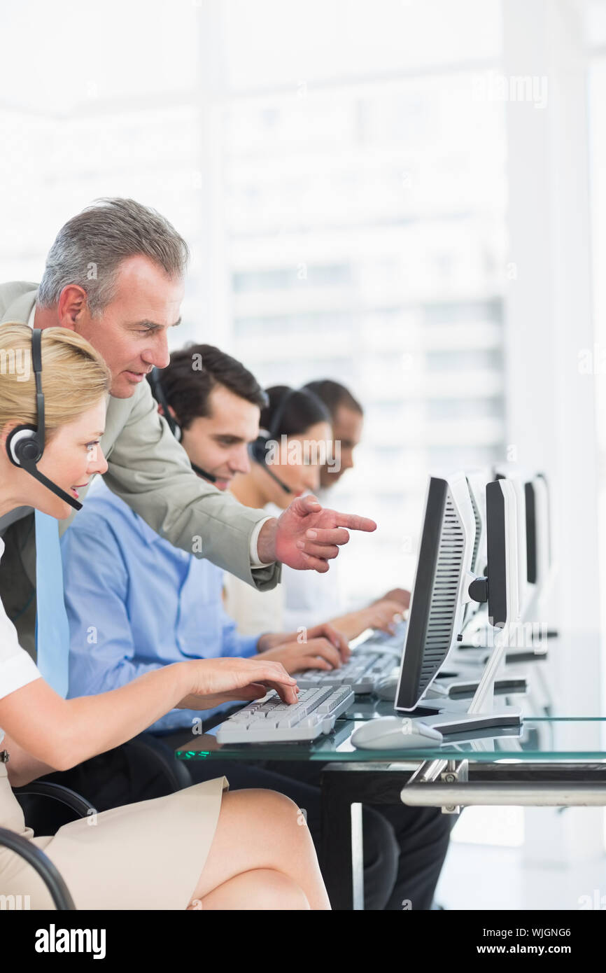 Side view of manager and executives with headsets using computers in ...
