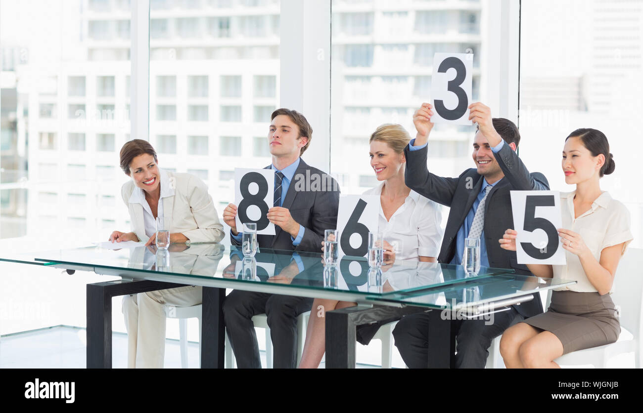 Group of panel judges in a row holding score signs Stock Photo - Alamy