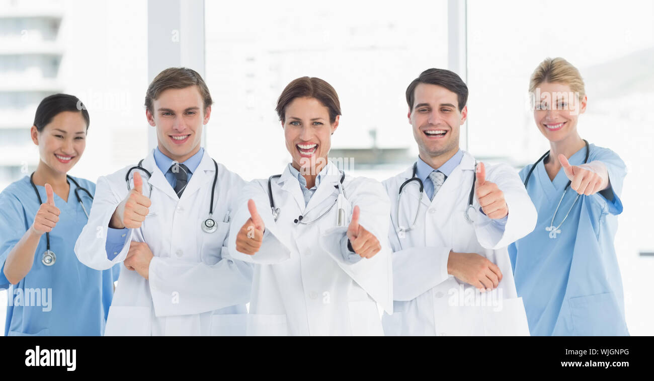 Group portrait of cheerful young doctors gesturing thumbs up at ...