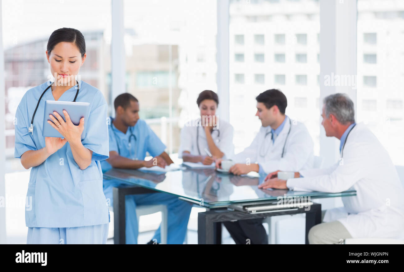 Female surgeon using digital tablet with group around table in ...