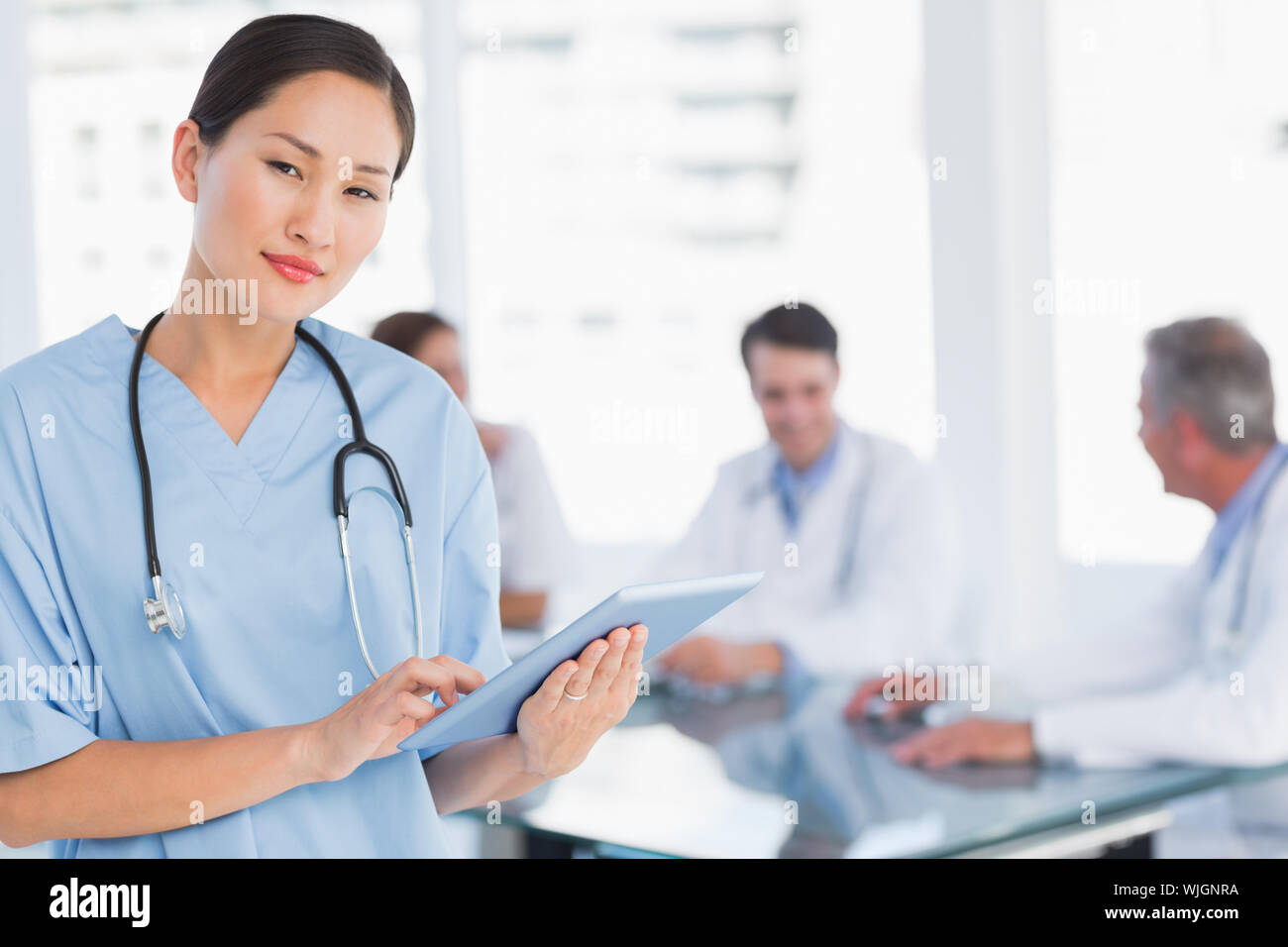 Female surgeon using digital tablet with group around table in ...