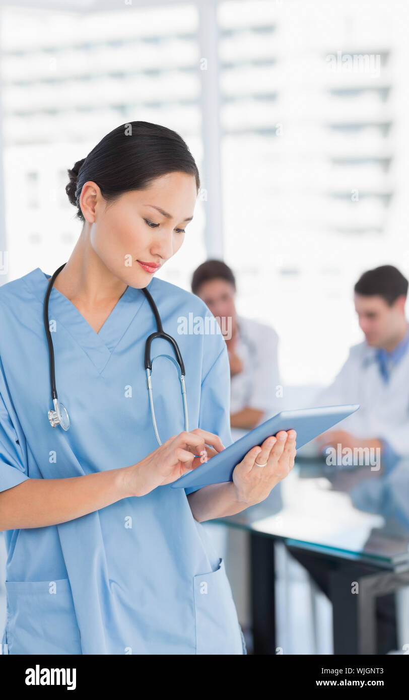 Female surgeon using digital tablet with group around table in ...