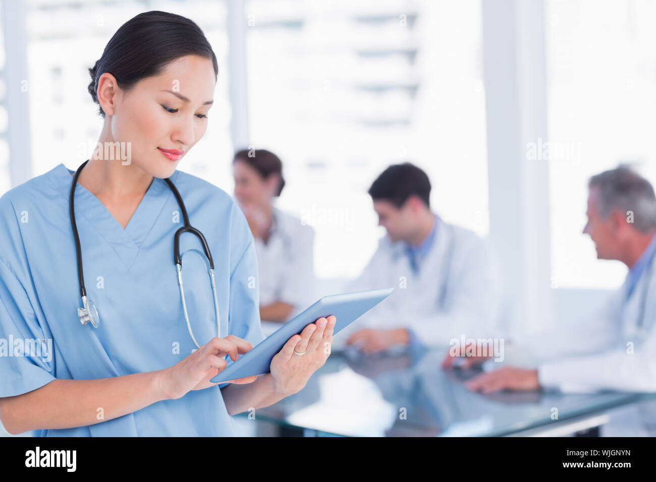 Female surgeon using digital tablet with group around table in ...