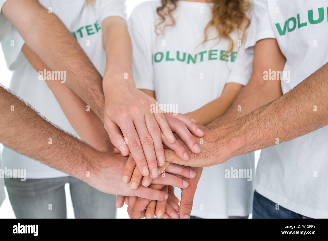 Close-up mid section of volunteers with hands together over white ...